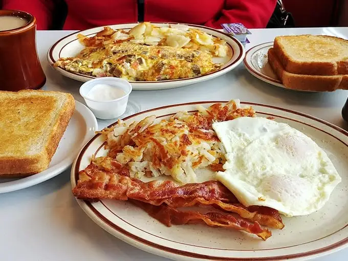 Breakfast perfection on a plate—crispy bacon, eggs with sunshine-yellow yolks, and hash browns that crackle with each forkful.