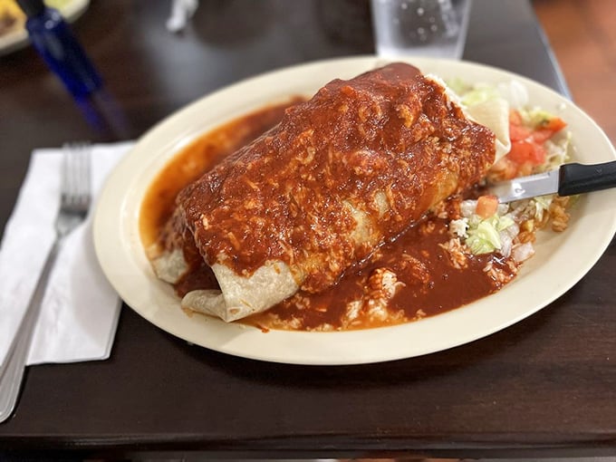 This smothered burrito isn't hiding under that sauce – it's basking in it, like a tortilla-wrapped treasure bathing in a pool of culinary glory.