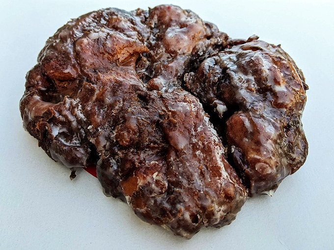 This apple fritter isn't just a donut—it's a topographical marvel of crispy peaks and valleys glistening with sweet glaze.