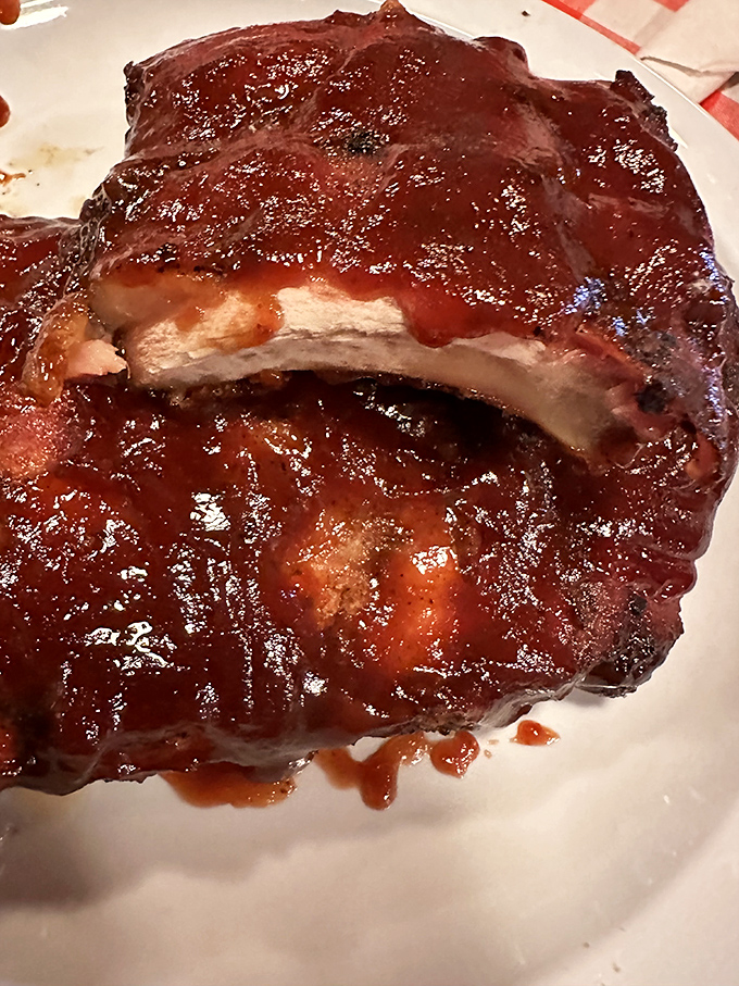 These ribs wear their sauce like a glossy coat of armor. The meat's not falling off the bone – it's making a graceful, dignified exit.