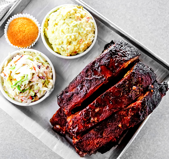 These ribs aren't just falling off the bone—they're practically jumping into your mouth while the sides cheer them on.