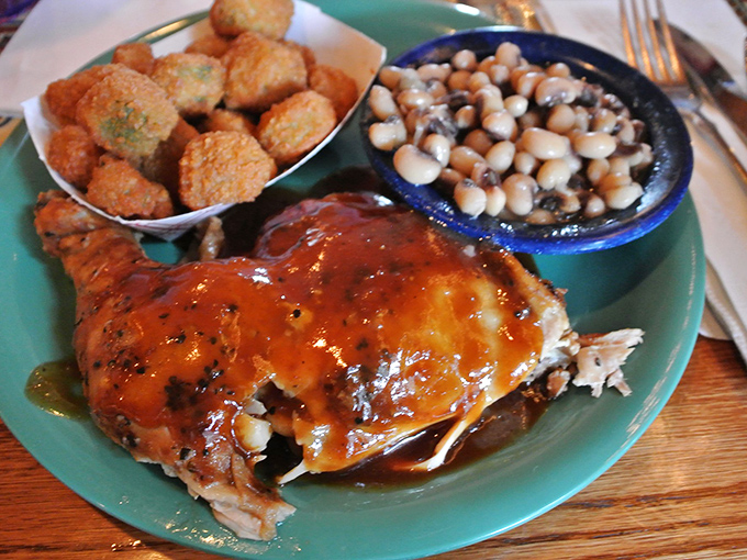 BBQ chicken wearing its sauce like a badge of honor, with black-eyed peas and corn fritters standing proudly alongside – a plate of Southern dignity. 
