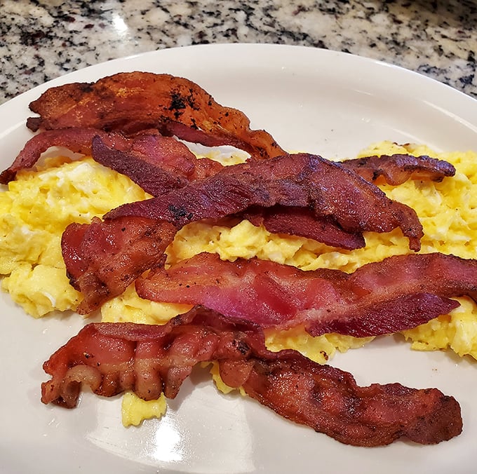The bacon and eggs tango – crispy strips performing a perfect dance across fluffy scrambled eggs. Breakfast doesn't get more iconic.