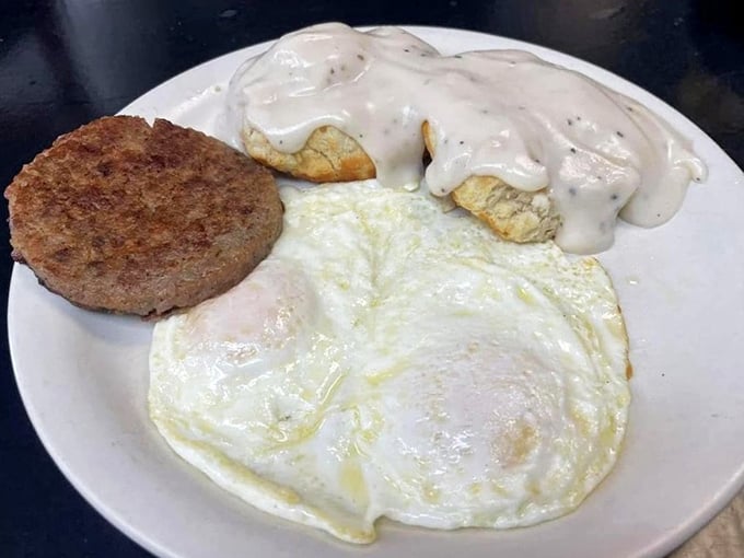 The holy trinity of breakfast: perfectly fried eggs, savory sausage, and biscuits swimming in gravy that could make a vegetarian reconsider.