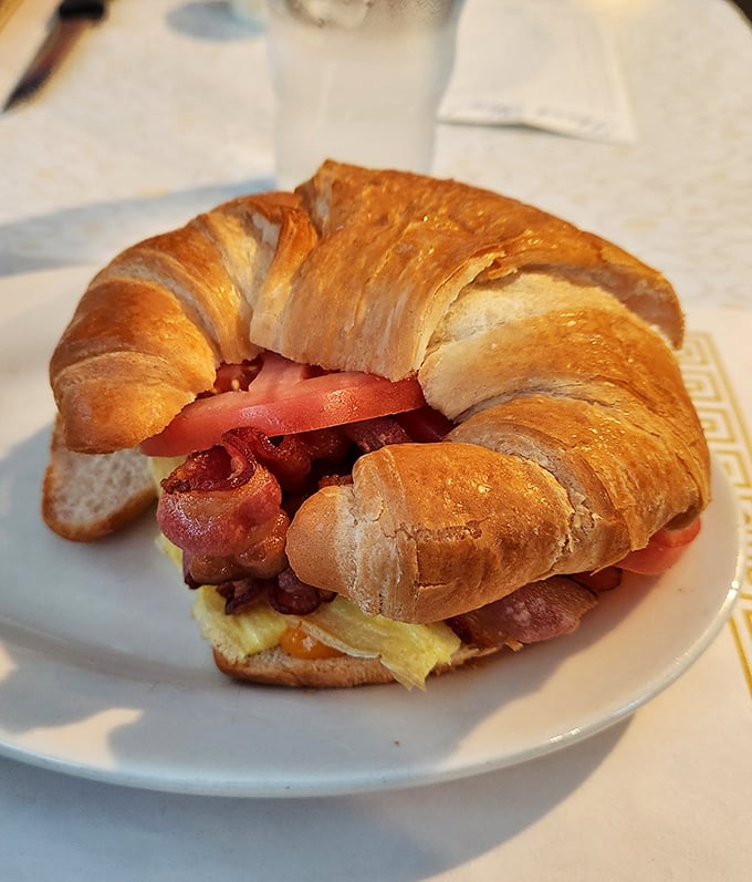 The breakfast sandwich that launched a thousand satisfied sighs. Flaky croissant, eggs, bacon, and cheese—morning's greatest hits album on a plate.