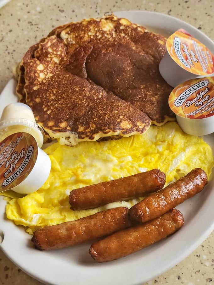 The breakfast trinity: perfectly cooked pancakes, scrambled eggs, and sausage links—a holy alliance on a single plate.
