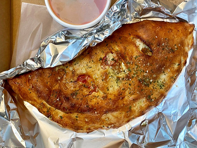 This isn't just a calzone—it's a golden-brown treasure chest filled with savory delights and served with marinara for extra dipping pleasure.