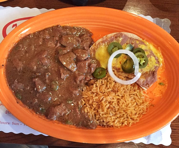 Carne Guisada that would make your abuela proud – tender beef swimming in rich gravy alongside Spanish rice and a cheese-topped tostada.