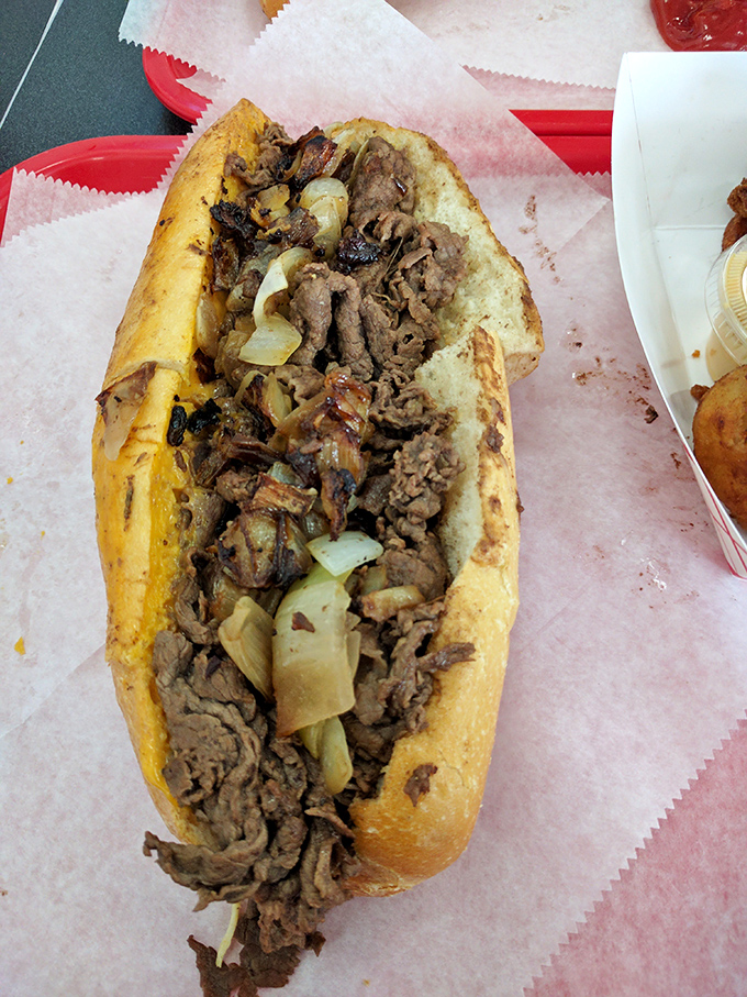 The cheesesteak in its natural habitat – overflowing with perfectly grilled meat and onions. A sandwich that demands both hands and your full attention.