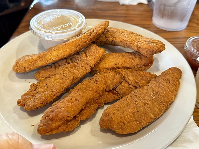 Golden-brown chicken tenders that achieve that perfect crunch-to-tenderness ratio, with dipping sauce standing by for its supporting role.