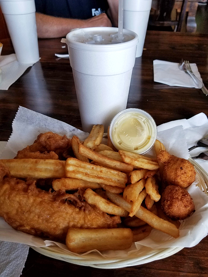 A basket of crispy chicken tenders, golden fries, and hushpuppies—comfort food's greatest hits album served on humble paper.