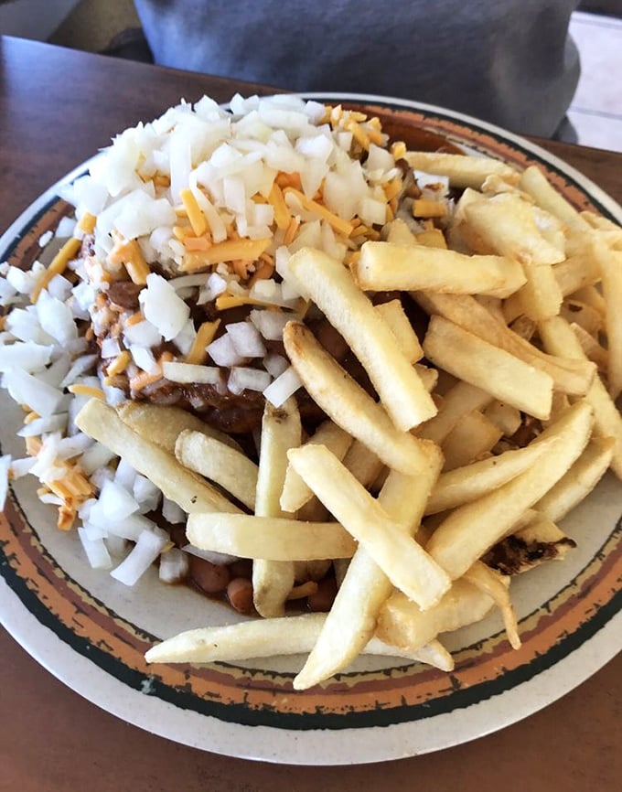 Chili cheese fries topped with diced onions: the holy trinity of late-night cravings served on one glorious plate.
