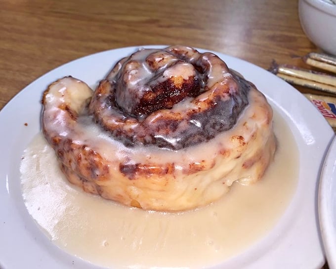 This isn't just a cinnamon roll—it's a spiral-shaped love letter to your taste buds. Swimming in a pool of warm icing that's worth every napkin.
