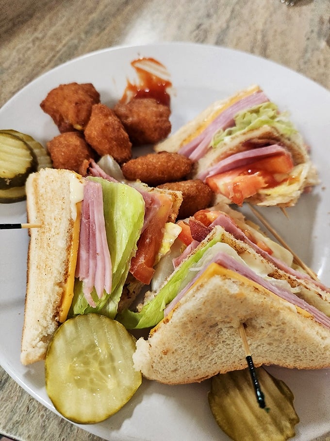 The club sandwich—architecture you can eat. Three perfectly toasted stories of bread supporting the delicious neighborhood of meat, cheese, and veggies.