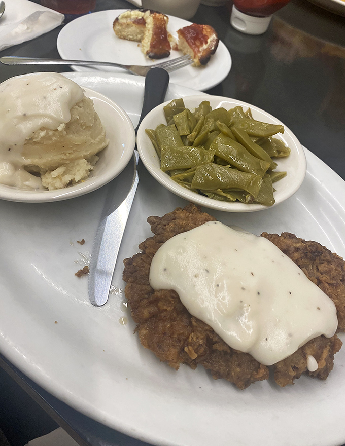Country fried steak wearing a blanket of peppery white gravy, with fresh green beans and mashed potatoes standing by as worthy sidekicks.