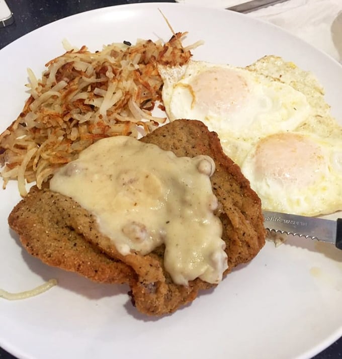 Country fried steak smothered in creamy gravy alongside crispy hash browns and eggs—the breakfast that says "go back to bed" and "conquer the world" simultaneously.