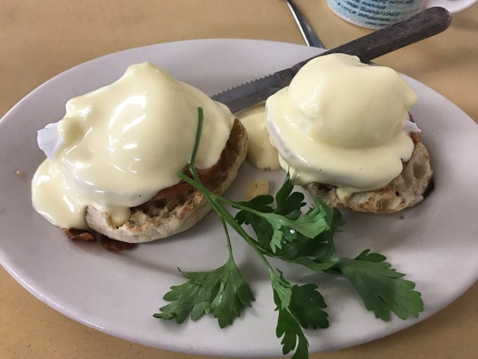 These eggs Benedict aren't messing around—hollandaise cascading down English muffin mountains with a sprig of parsley standing guard.