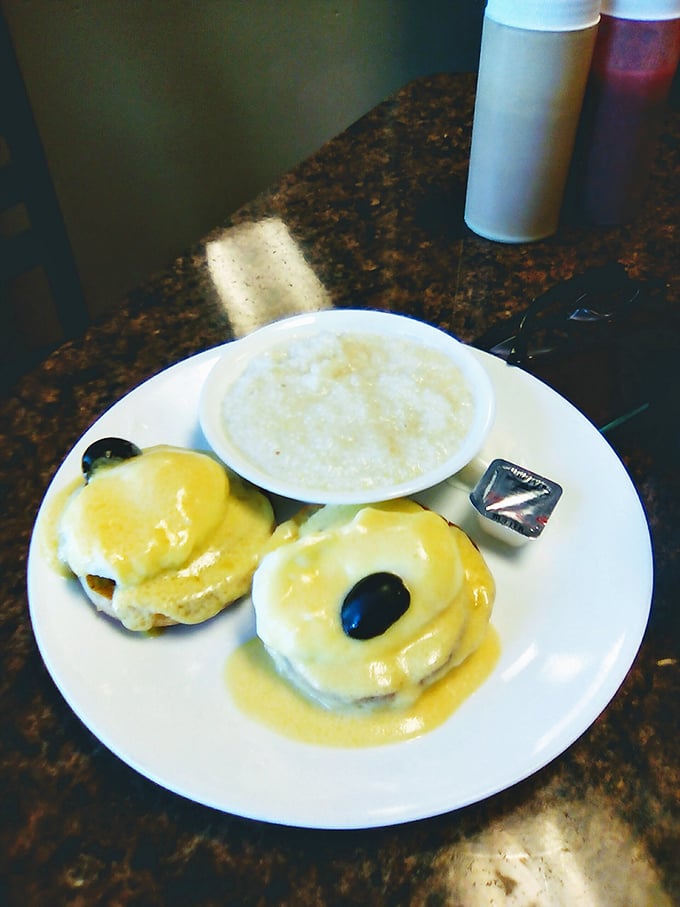 Behold the star attraction: Eggs Benedict with hollandaise so golden it deserves its own Fort Knox, served with a side of creamy grits.