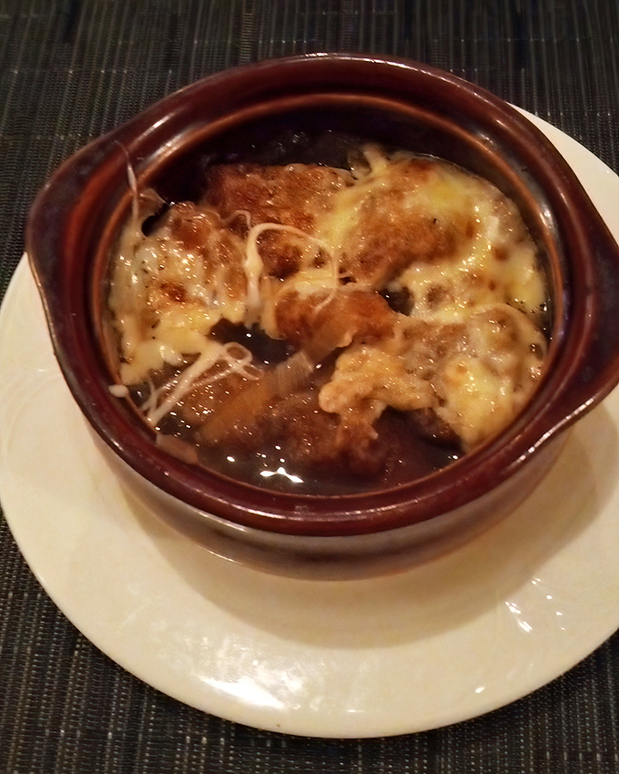 This isn't just French onion soup—it's a cheese-crowned comfort in a crock, where bread islands float in a savory broth sea.