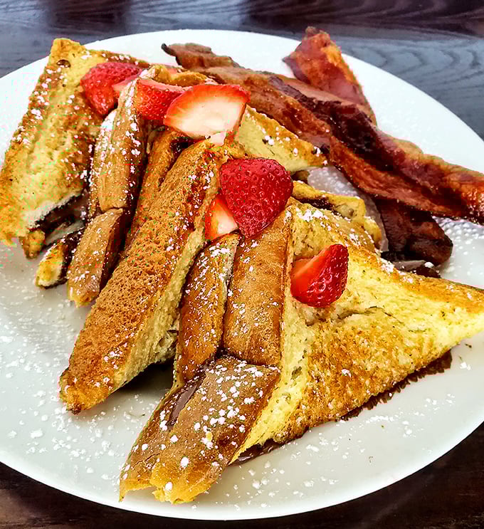French toast triangles dusted with powdered sugar and crowned with strawberries—the breakfast equivalent of wearing a tuxedo to the beach.
