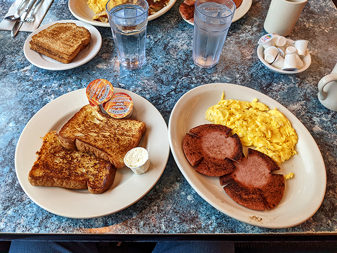 The breakfast classic duo—golden-brown French toast meeting perfectly scrambled eggs and sausage patties on their daily pilgrimage to breakfast perfection.