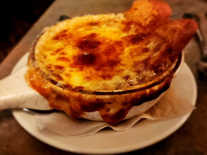 This isn't just French onion soup—it's a cheese-capped caldron of comfort that demands to be broken into with gleeful abandon.