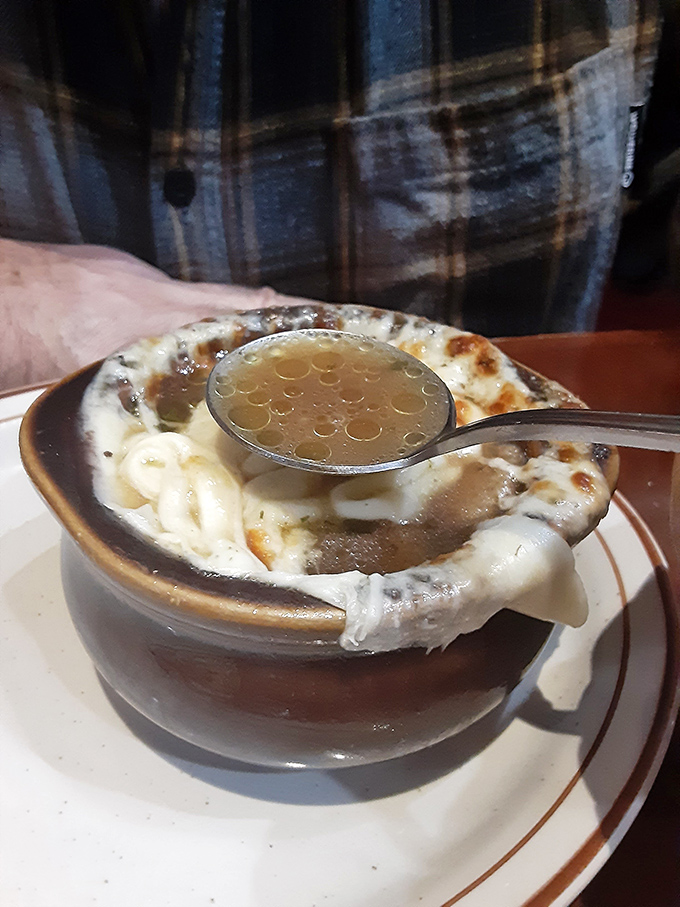 French onion soup that's worth the cheese pull—a bubbling cauldron of savory broth crowned with a magnificent melted canopy.