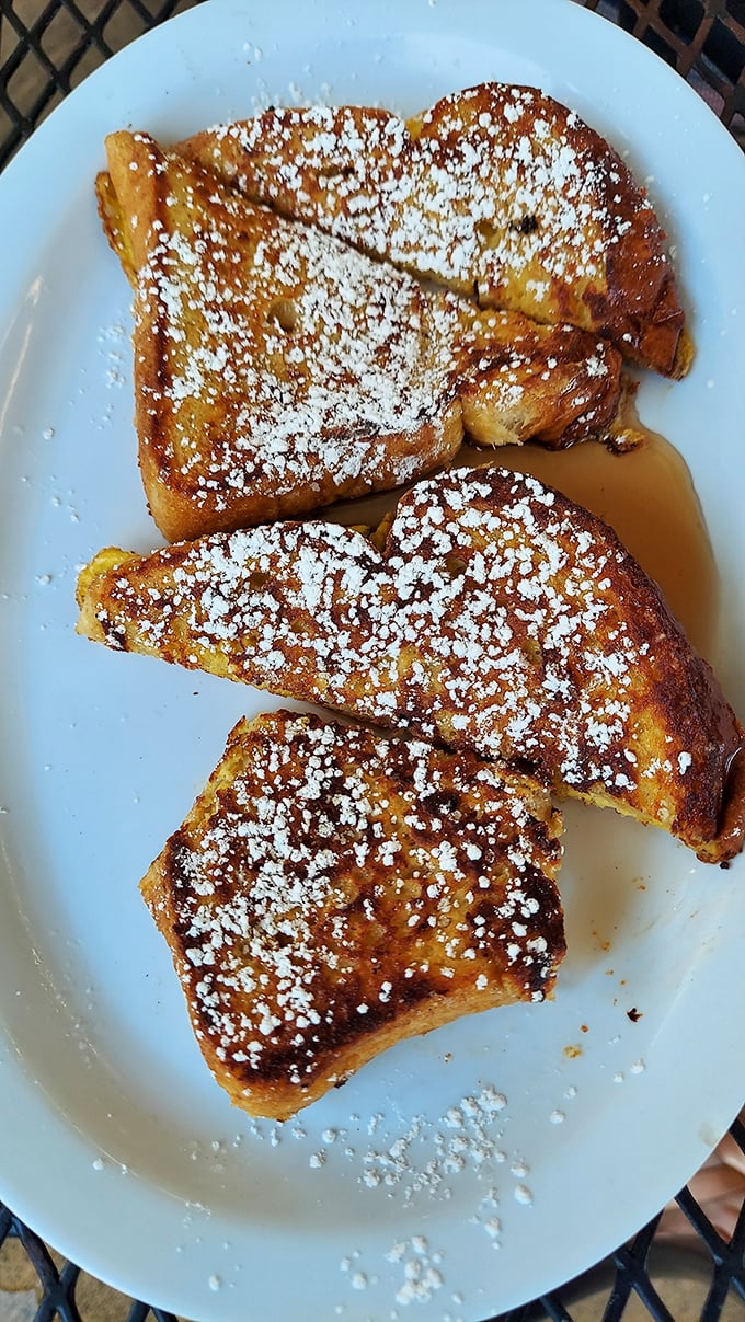French toast dusted with powdered sugar like fresh snow on Christmas morning. Three golden triangles of bread that have achieved breakfast nirvana.