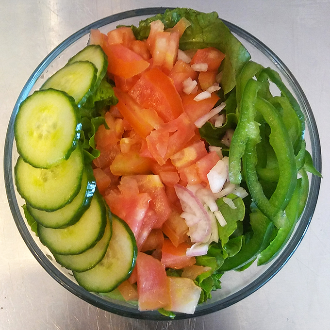 A garden salad that actually looks like it came from a garden—crisp cucumbers, juicy tomatoes, and greens arranged with the care usually reserved for dishes costing four times as much.