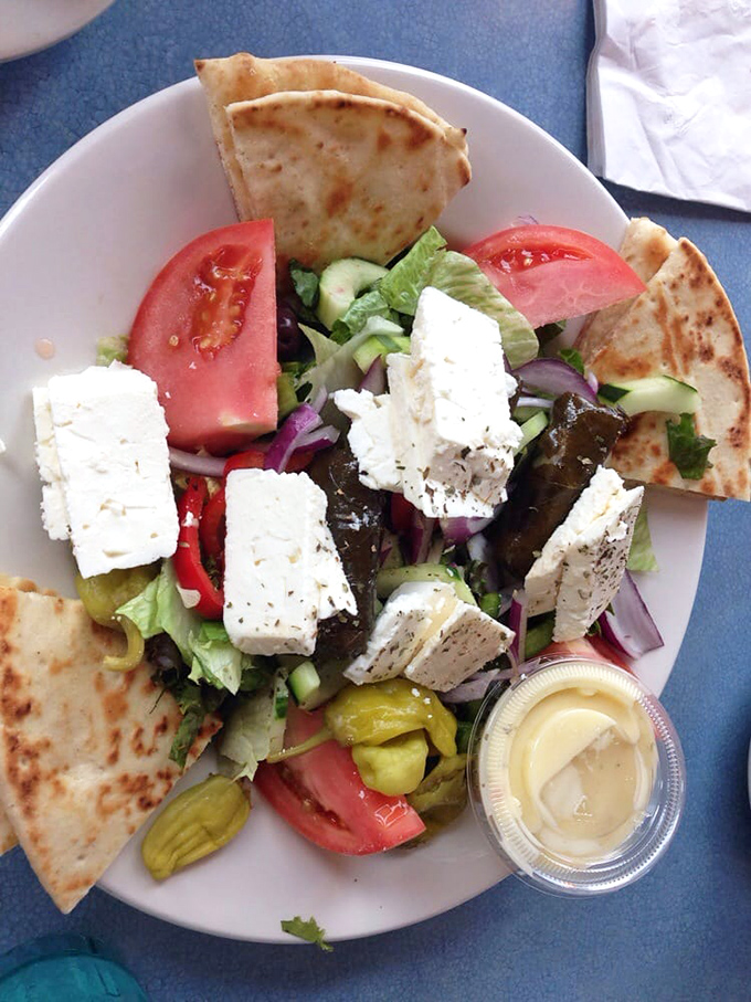 The Greek salad arrives looking like it just stepped off a Mediterranean vacation – crisp, bright, and unapologetically loaded with feta.