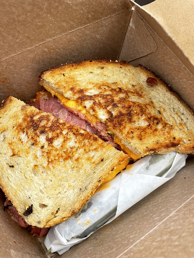 The grilled sandwich in its natural habitat – a cardboard container that barely contains the melty, meaty magnificence within.