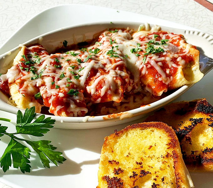 Italian comfort meets diner ingenuity—these cheese-blanketed manicotti are like warm hugs served on ceramic, with garlic bread standing by for backup.