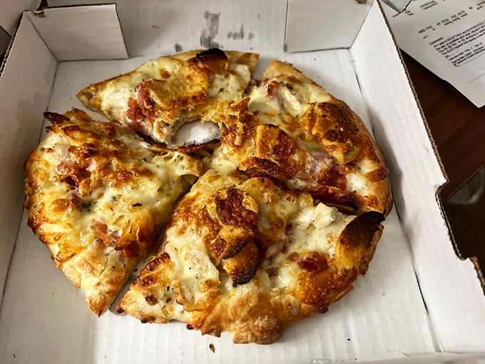 The Montana pizza emerges from its box like a work of art that somehow survived shipping—a miracle of cheese and crust.