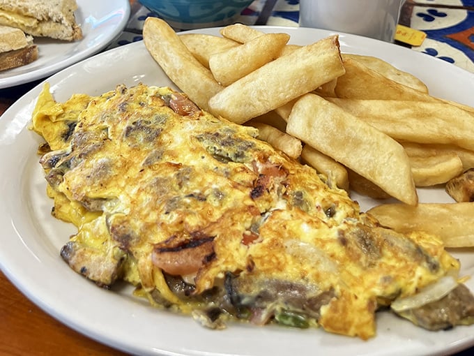 This isn't just an omelet—it's a fluffy yellow canvas painted with savory ingredients and paired with potato perfection.