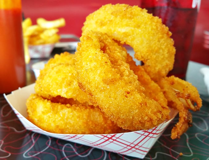 Onion rings like gold medals for your taste buds – crispy, golden halos that shatter satisfyingly between your teeth, revealing sweet onion treasure inside.