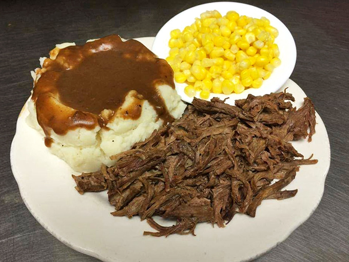 Mashed potatoes drowning happily in gravy, tender pot roast, and sweet corn—the holy trinity of Midwestern comfort on a single plate.