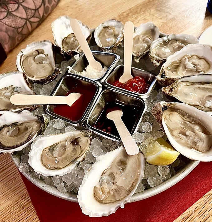 A dozen glistening oysters on ice, surrounded by colorful condiments—nature's perfect appetizer waiting for a squeeze of lemon and a moment of appreciation.