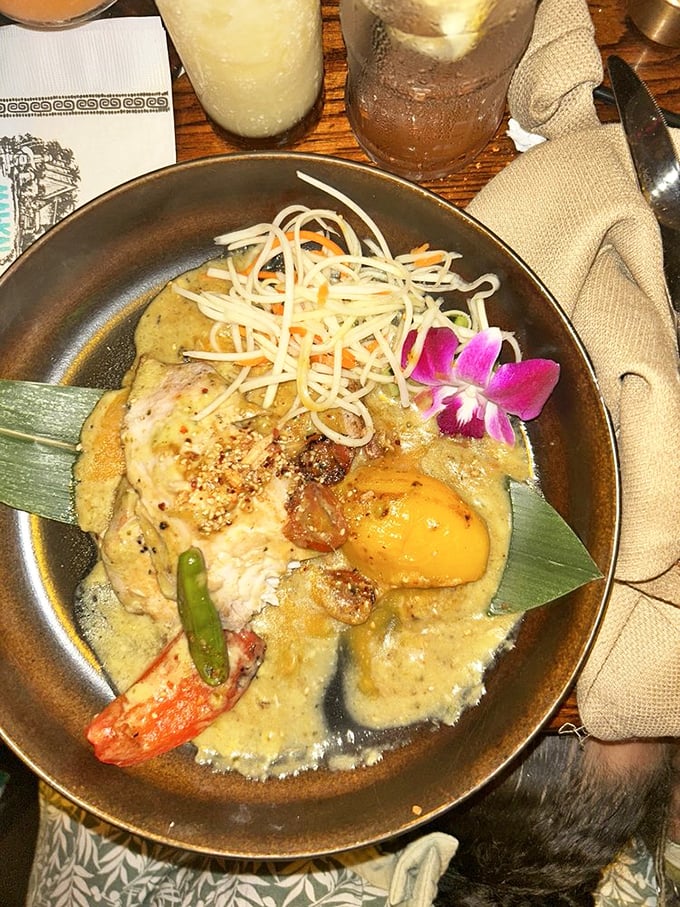 A curry that doesn't just sit on the plate—it tells a story with every spoonful, complete with a fresh orchid garnish that's almost too pretty to eat. Almost.