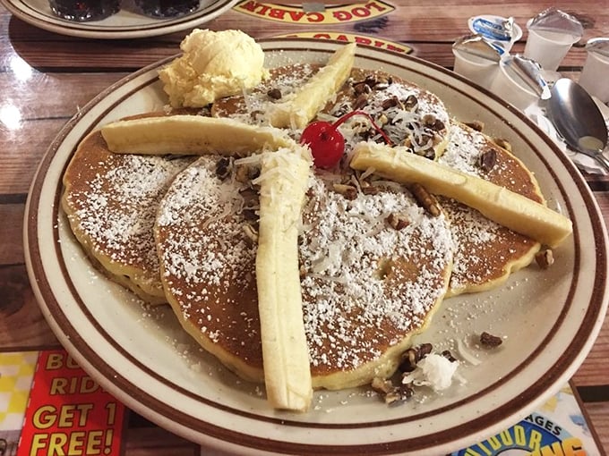 Pancakes adorned with bananas, powdered sugar, and what appears to be a cherry on top—breakfast masquerading as dessert, and nobody's complaining.