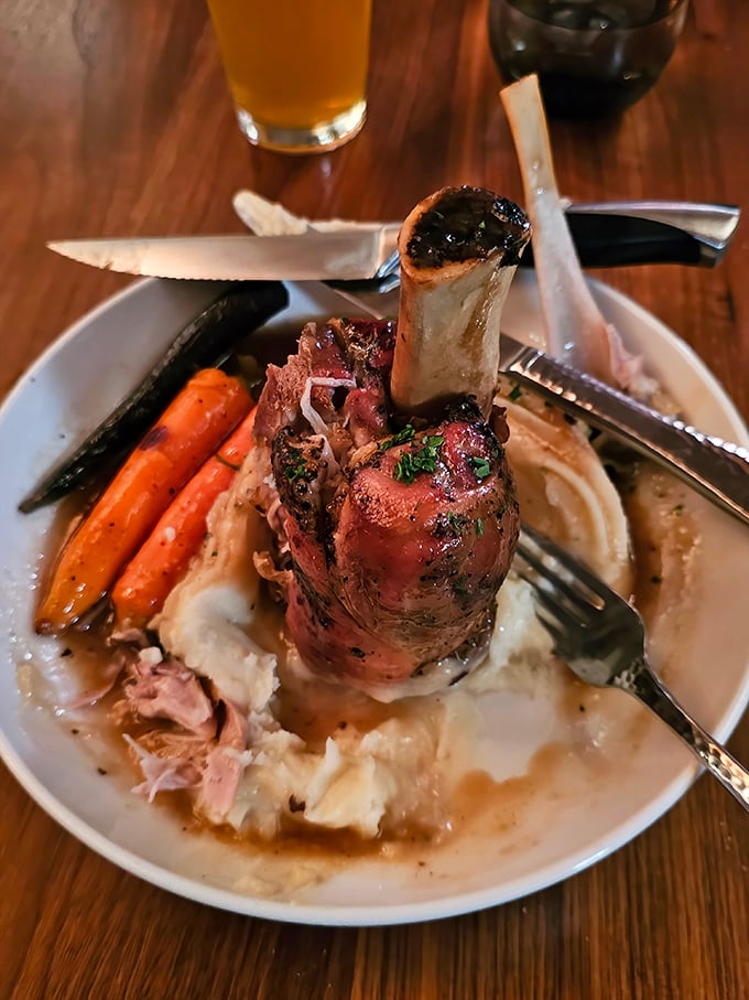 This isn't just dinner – it's architecture. The pork shank stands proudly over whipped potatoes like a meaty monument to comfort food excellence.