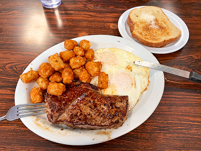 The classic steak and eggs, where a juicy cut meets perfectly crispy tater tots—proof that simplicity, done right, is culinary genius.
