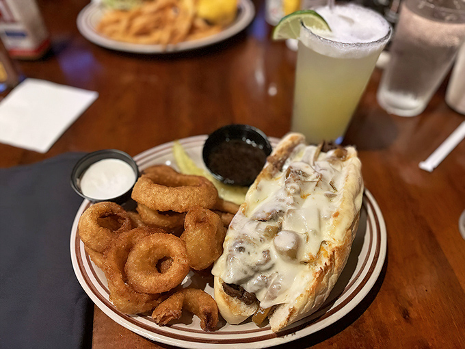 When a sandwich requires both hands and your full attention—tender prime rib nestled in bread with golden onion rings standing guard.