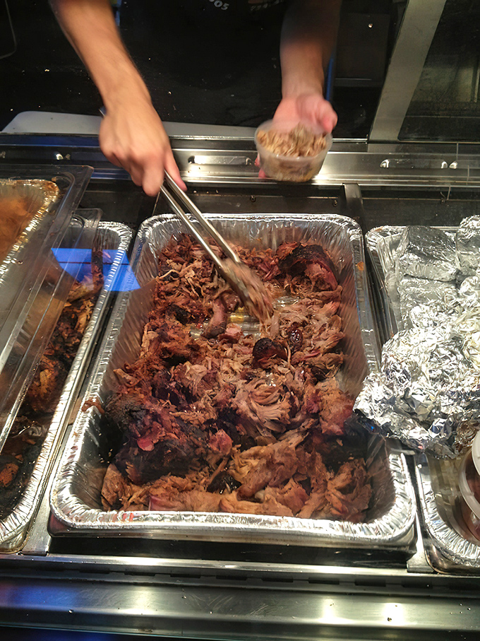 Someone's hands orchestrating the pulled pork symphony—each strand of meat conducting flavor directly to your taste buds.