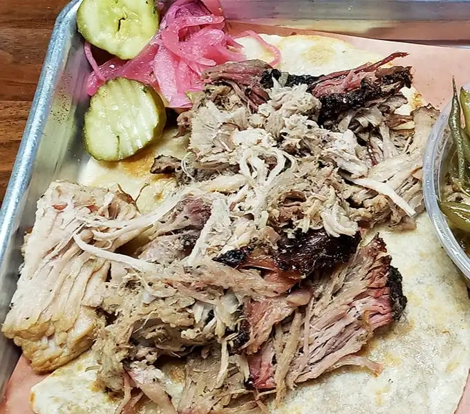 Pulled pork so tender it practically pulled itself. Those pickles and onions aren't garnish—they're essential supporting characters.