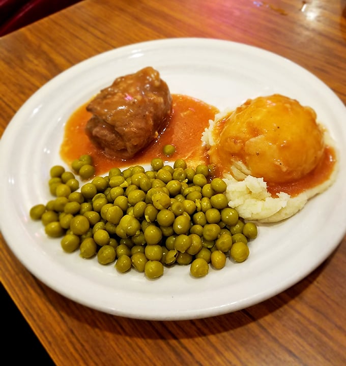 Old-school comfort: A tender rolled steak swimming in rich gravy alongside mashed potatoes and peas—like a hug from your grandmother.