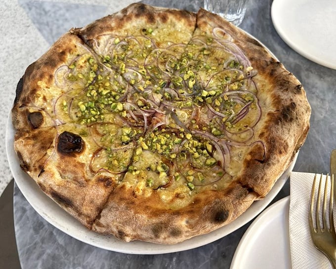 The Rosa pizza showcases red onion, pistachios, and rosemary—a combination that sounds odd until you taste it. Then it becomes obvious genius.