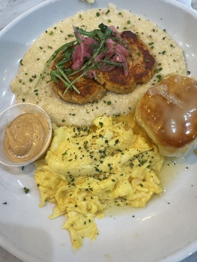 Salmon cakes nestled on a cloud of grits with eggs and a honey butter biscuit—proof that brunch isn't just a meal, it's an art form.