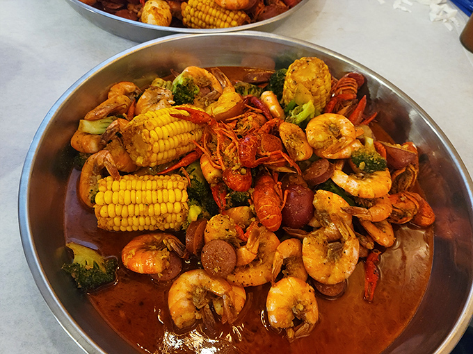The main event arrives! A glorious medley of shrimp, crawfish, corn, and sausage swimming in spiced glory—proof that the best parties happen in metal bowls.