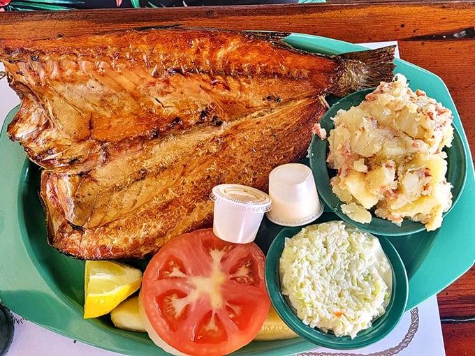 The smoked mullet dinner arrives like a smoky centerpiece with German potato salad and coleslaw sidekicks. Florida's seafood heritage on a turquoise plate.