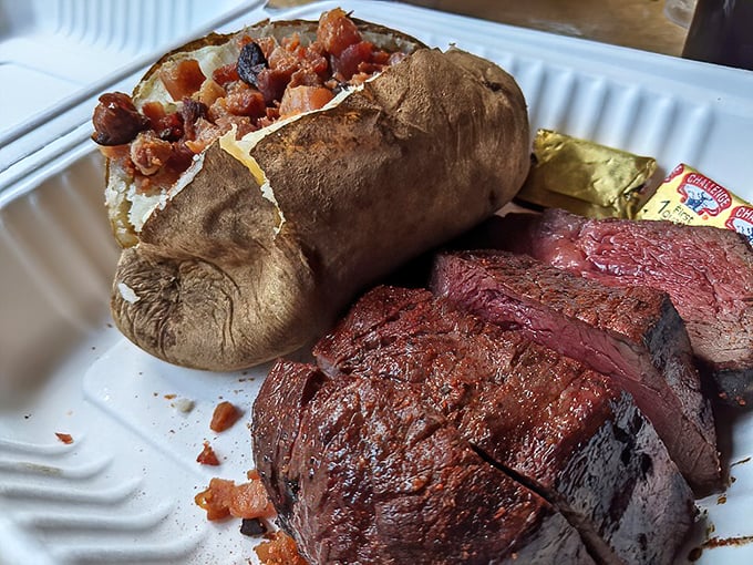 A baked potato loaded like a freight train next to steak with the perfect char—proof that heaven exists and it tastes like oak smoke.